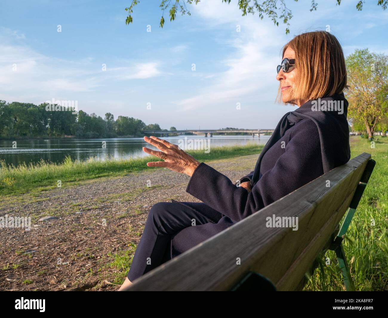 adult mature elegant caucasian woman sitting on a park bench with legs ...