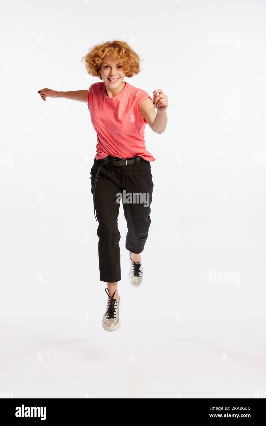 Excited beautiful young redheaded woman running isolated on white ...