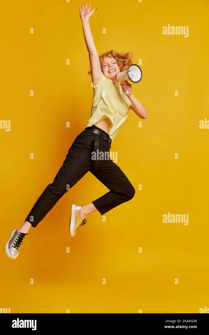 Full-length portrait of active young red-haired girl jumping with ...