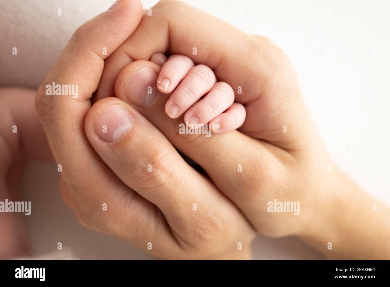 A newborn holds on to mom's, dad's finger. Hands of parents and baby ...