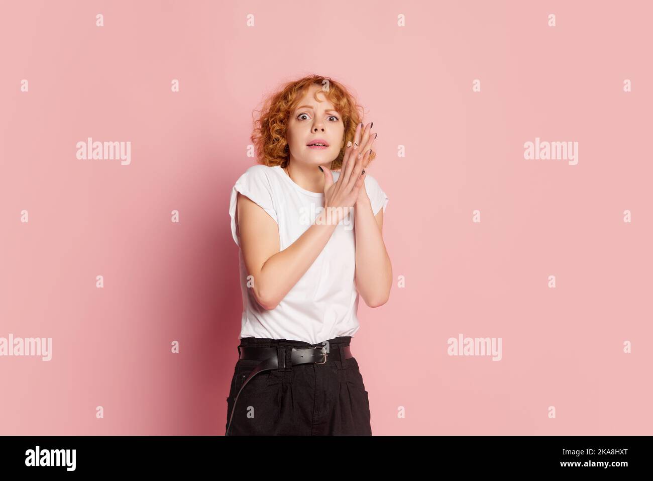 Scared young girl with curly hair wearing white t-shirt looking at ...