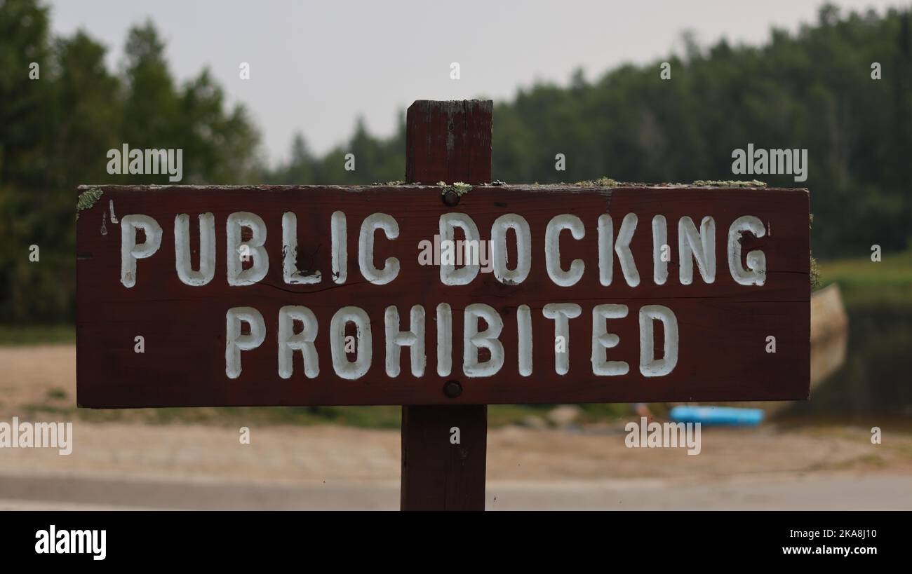 A wooden information sign with writing "Public Docking Prohibited" on a ...