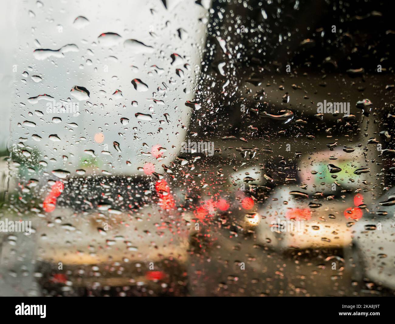 Traffic in rainy day with road view through car window with rain drops ...