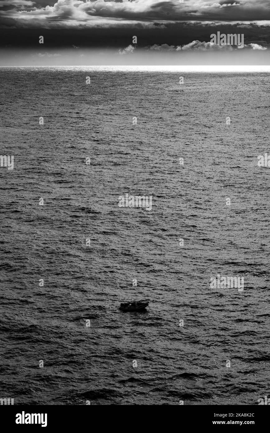 A vertical grayscale shot of the boat floating on the sea surface ...