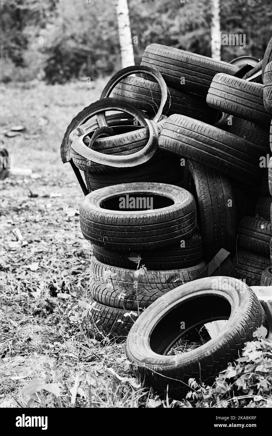 A grayscale shot of a pile of old used car tires on the grass Stock ...