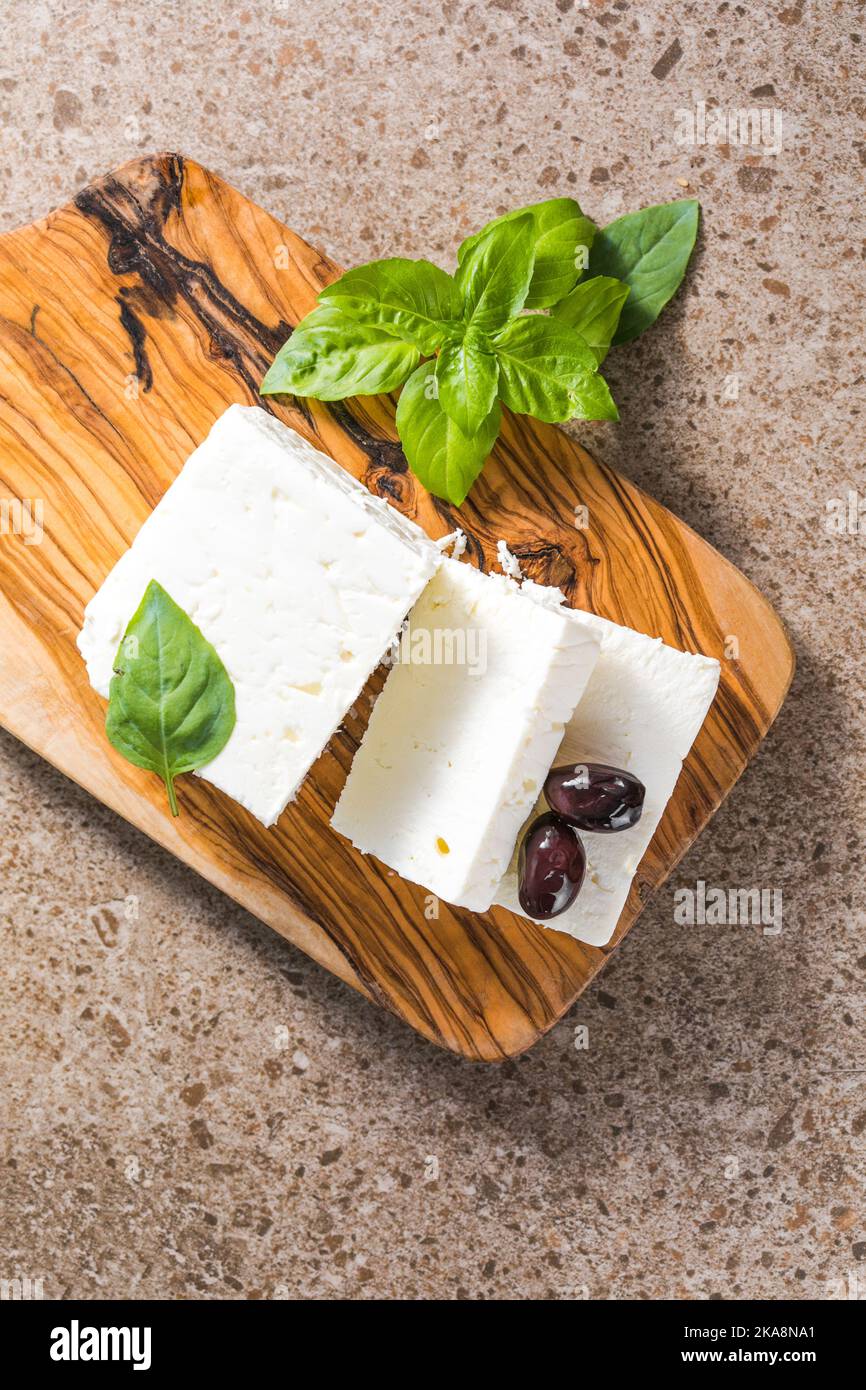 Feta cheese with olives and basil on a bamboo chopping board. The most ...