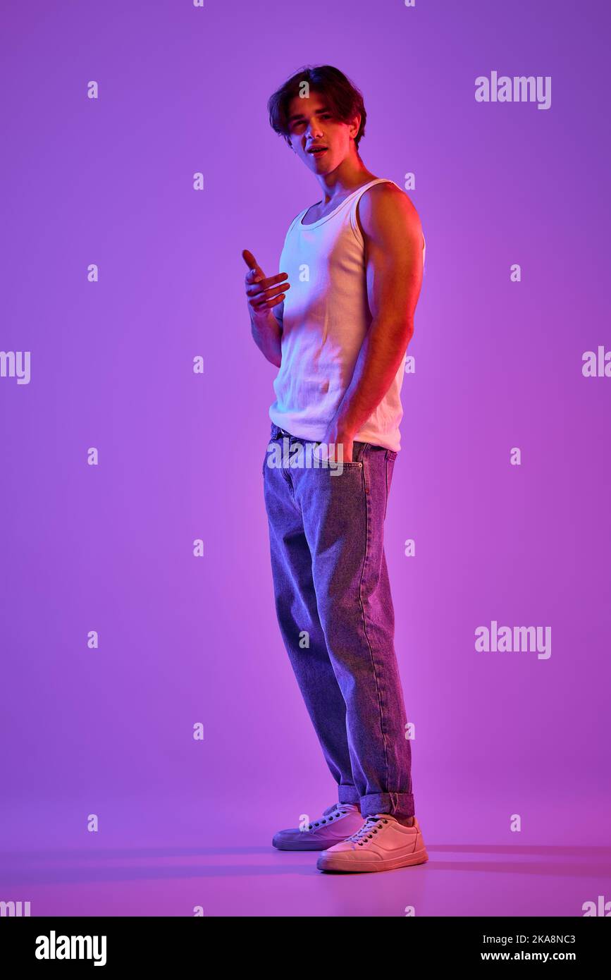 Portrait of young muscular man in white T-shirt, singlet posing over ...