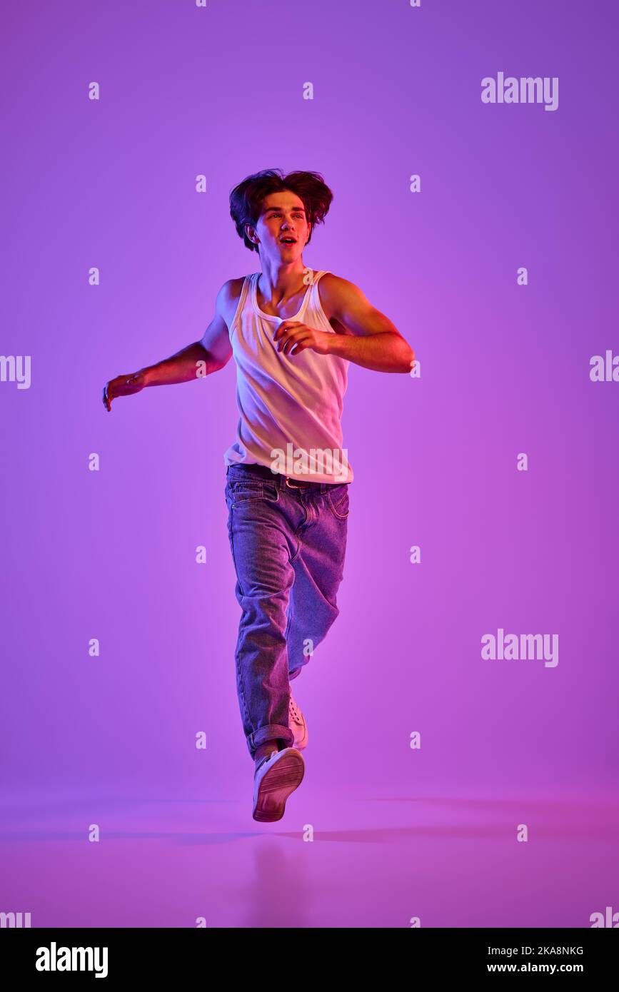 Portrait of young muscular man in white T-shirt, singlet posing in a ...