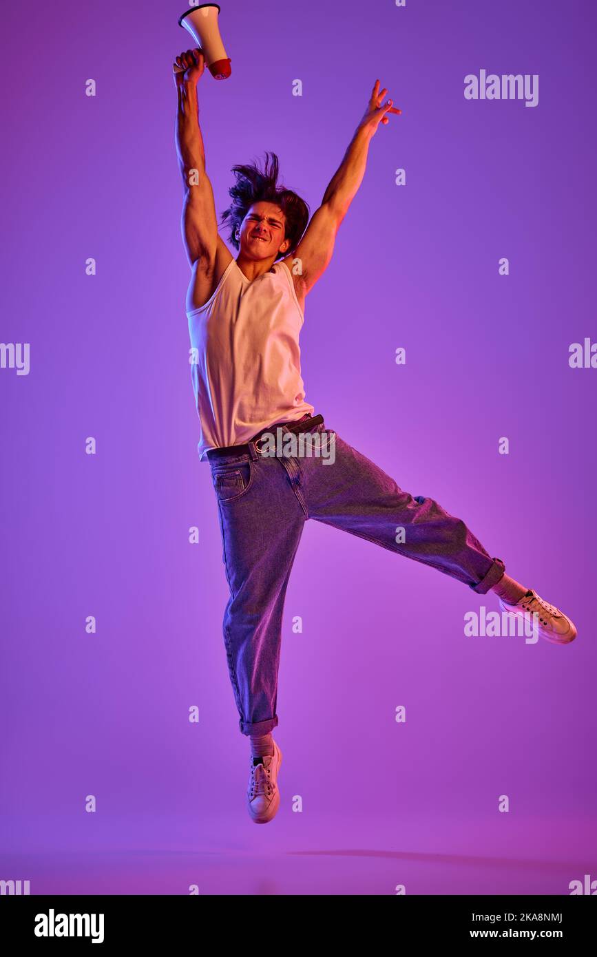 Portrait of young man in white T-shirt, singlet cheerfully jumping with ...