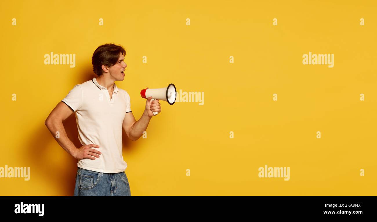 Portrait of young man in casual white T-shirt posing, talking in ...