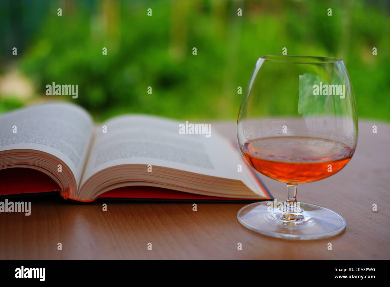 Whiskey in snifter glass and book outdoor on table Stock Photo - Alamy