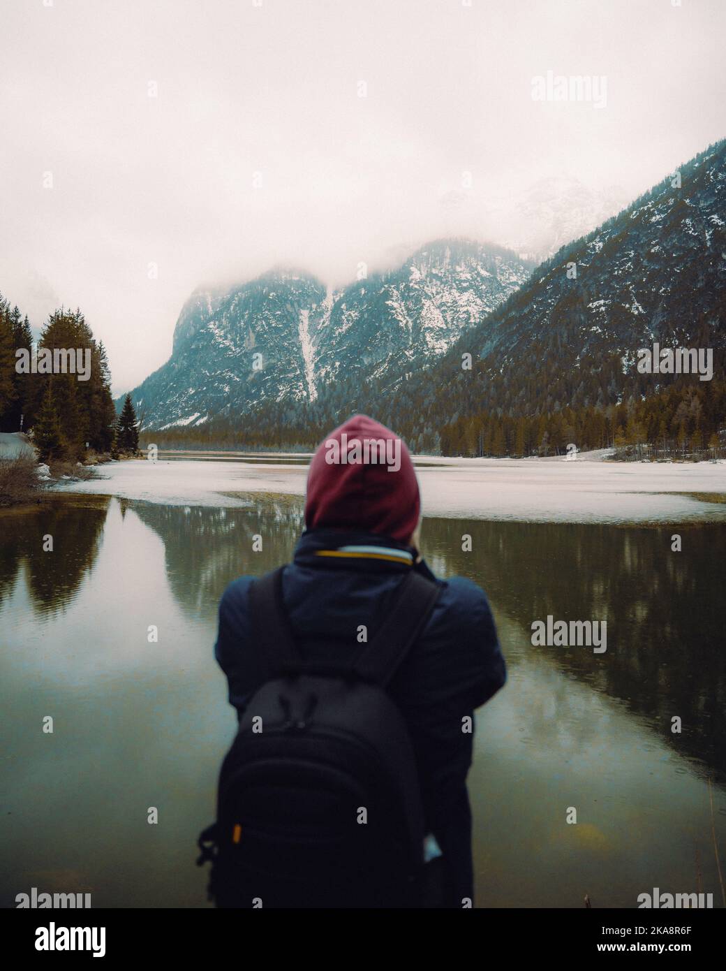 A vertical rear view of a tourist in a backpack enjoying the snowy ...