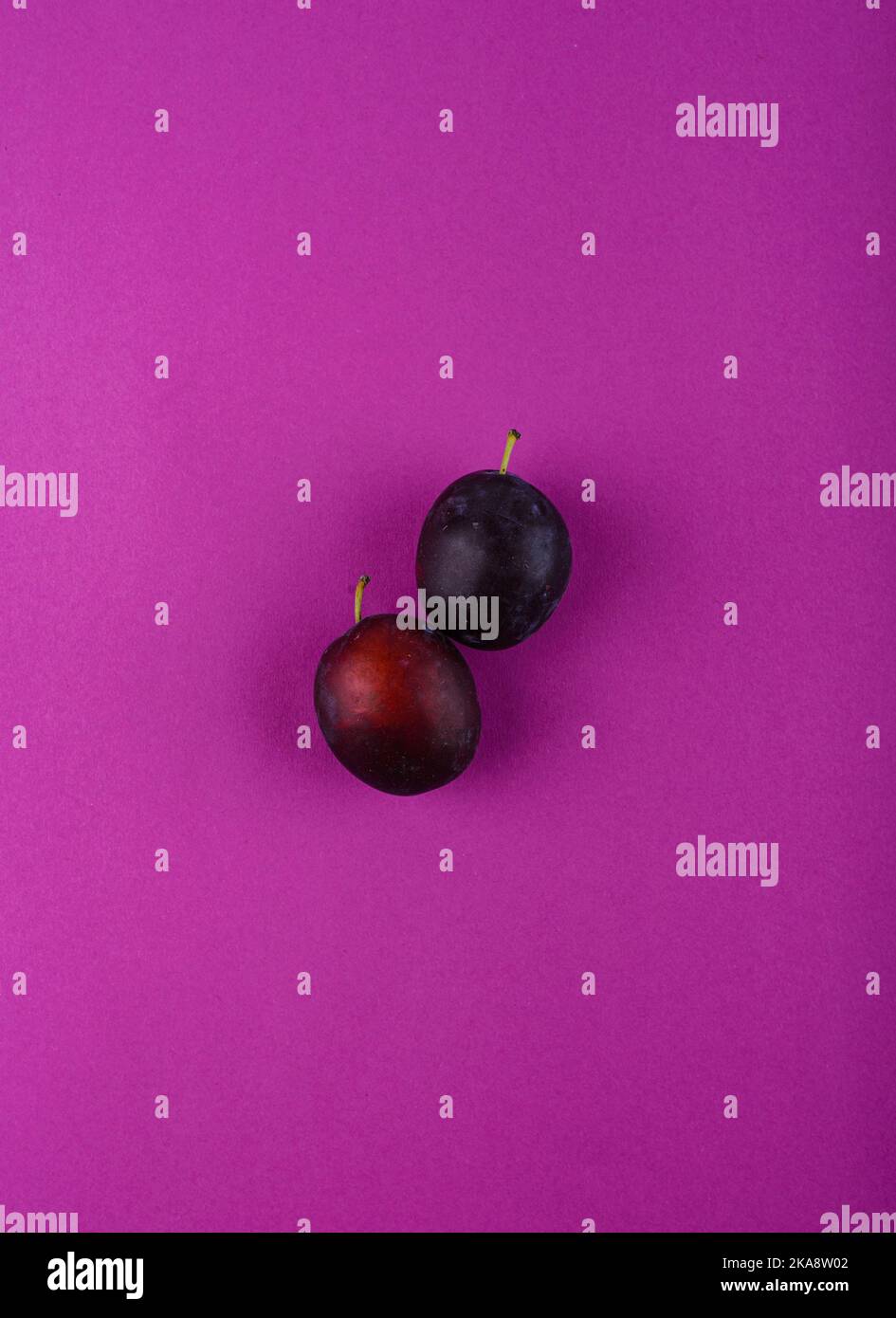Sweet ripe plums on purple violet background Stock Photo - Alamy