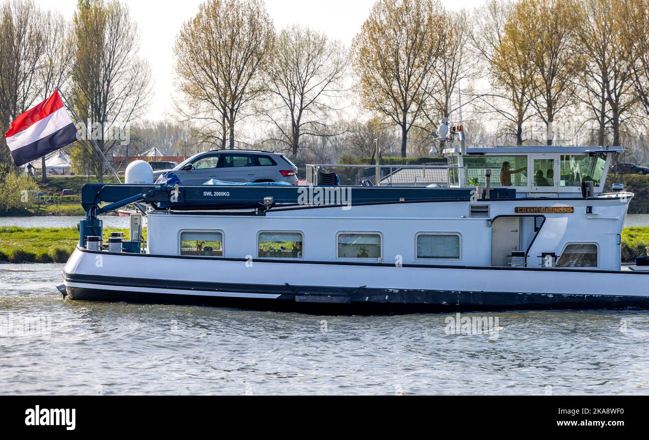 A cargo boat on the river Maas in Roermond with the Dutch flag hanging ...