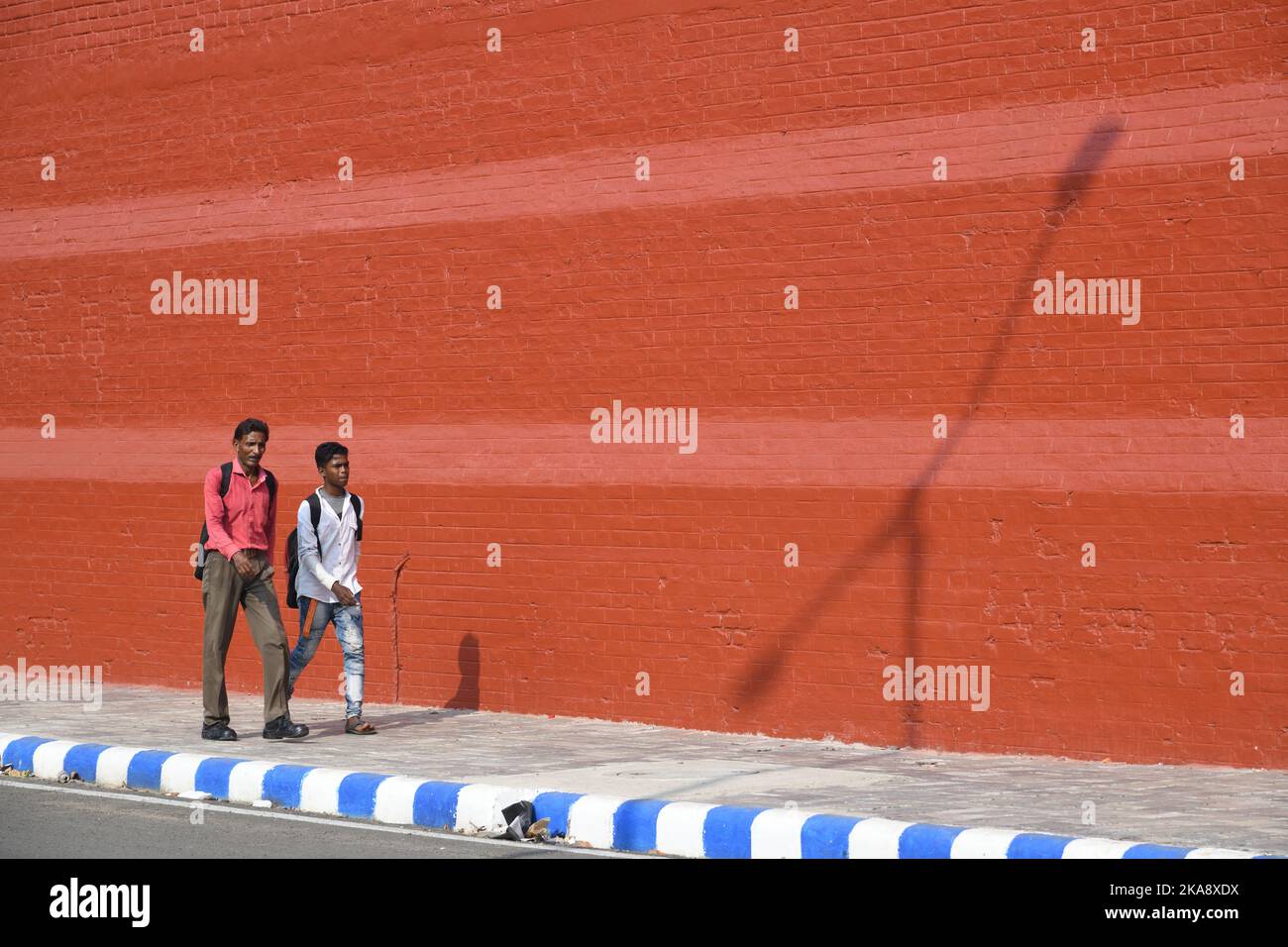 Two men walking against red boundary wall of Alipore Jail Museum ...