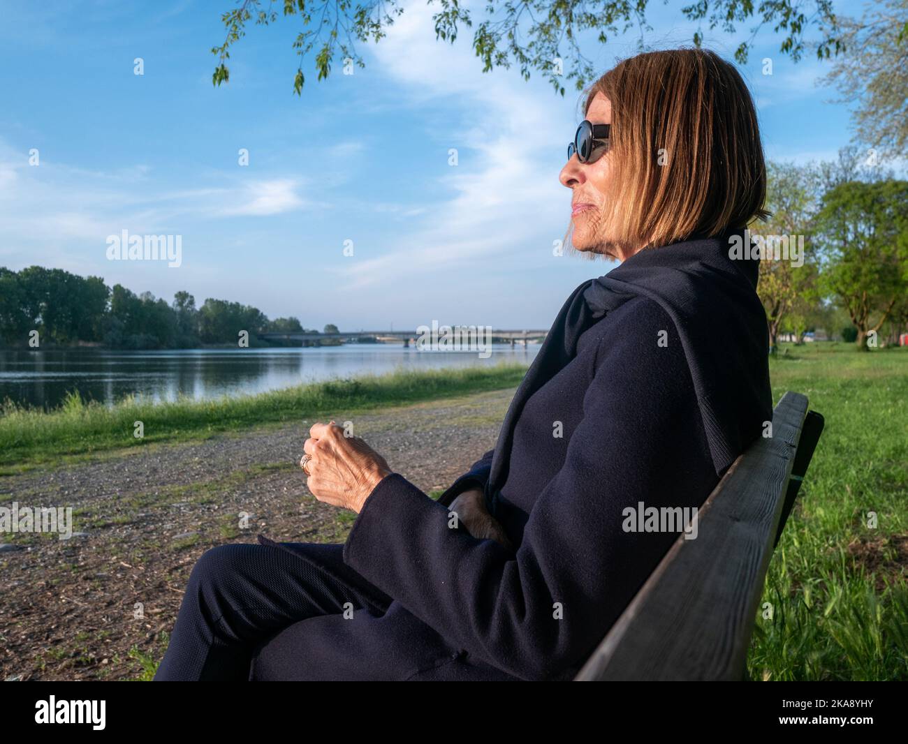 adult mature elegant caucasian woman sitting on a park bench with legs ...