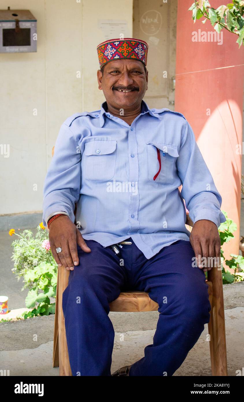 A vertical shot of an adult Indian man wearing a traditional hat ...