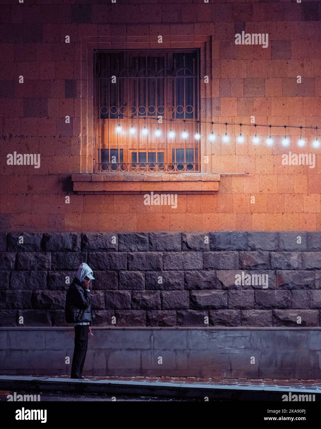 A vertical side view of a person standing in front of a building wall ...