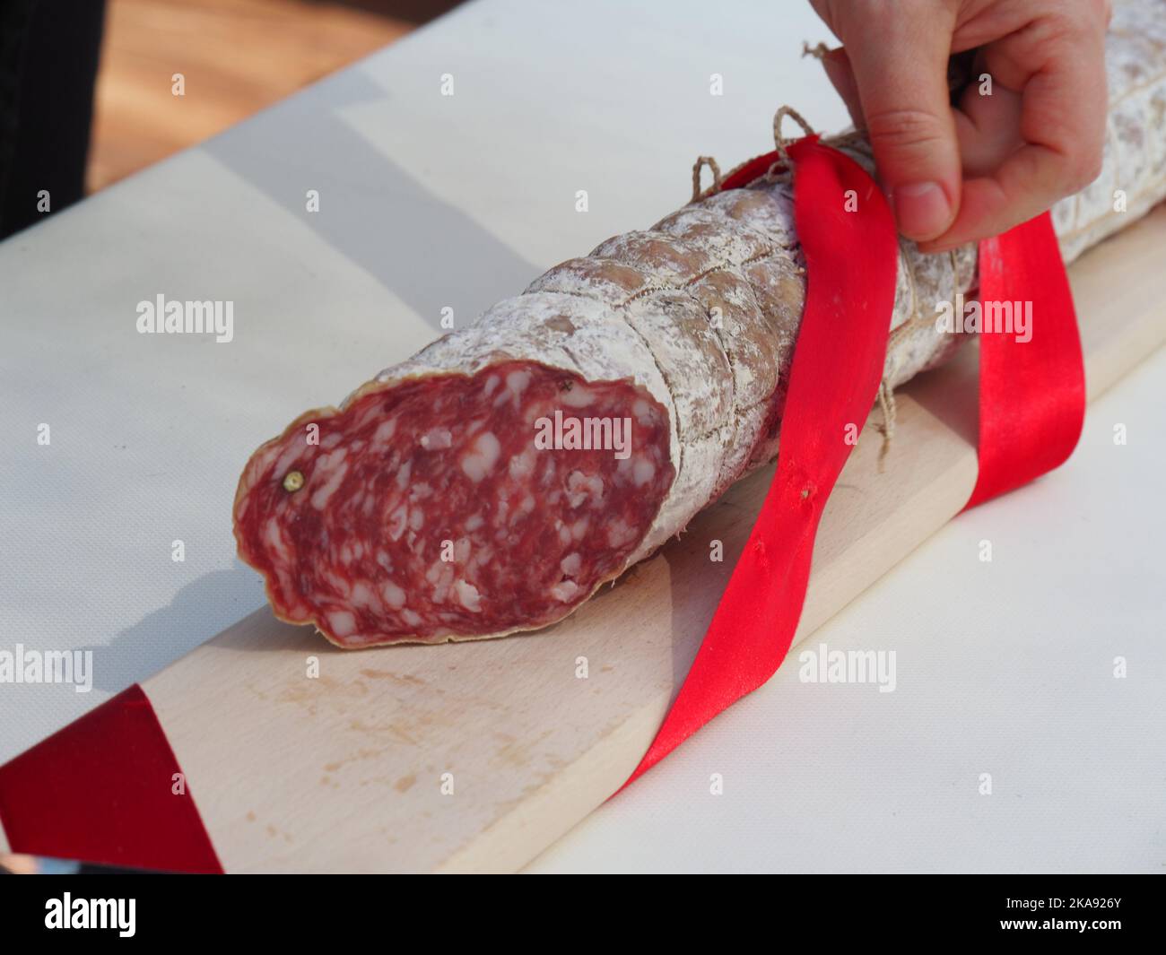catering and waiting staff hand with knife slicing salami ham in a ...
