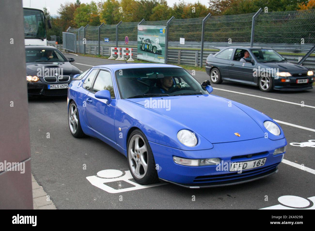 A closeup of a blue Porsche 968 sports car on a queue to be driven on ...
