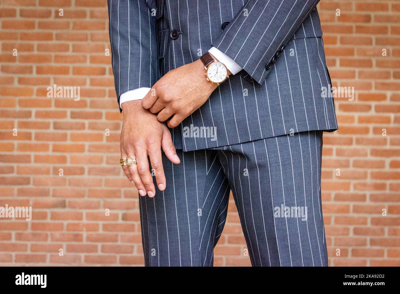A man in a beautiful blue suit wearing a watch standing in front of a ...