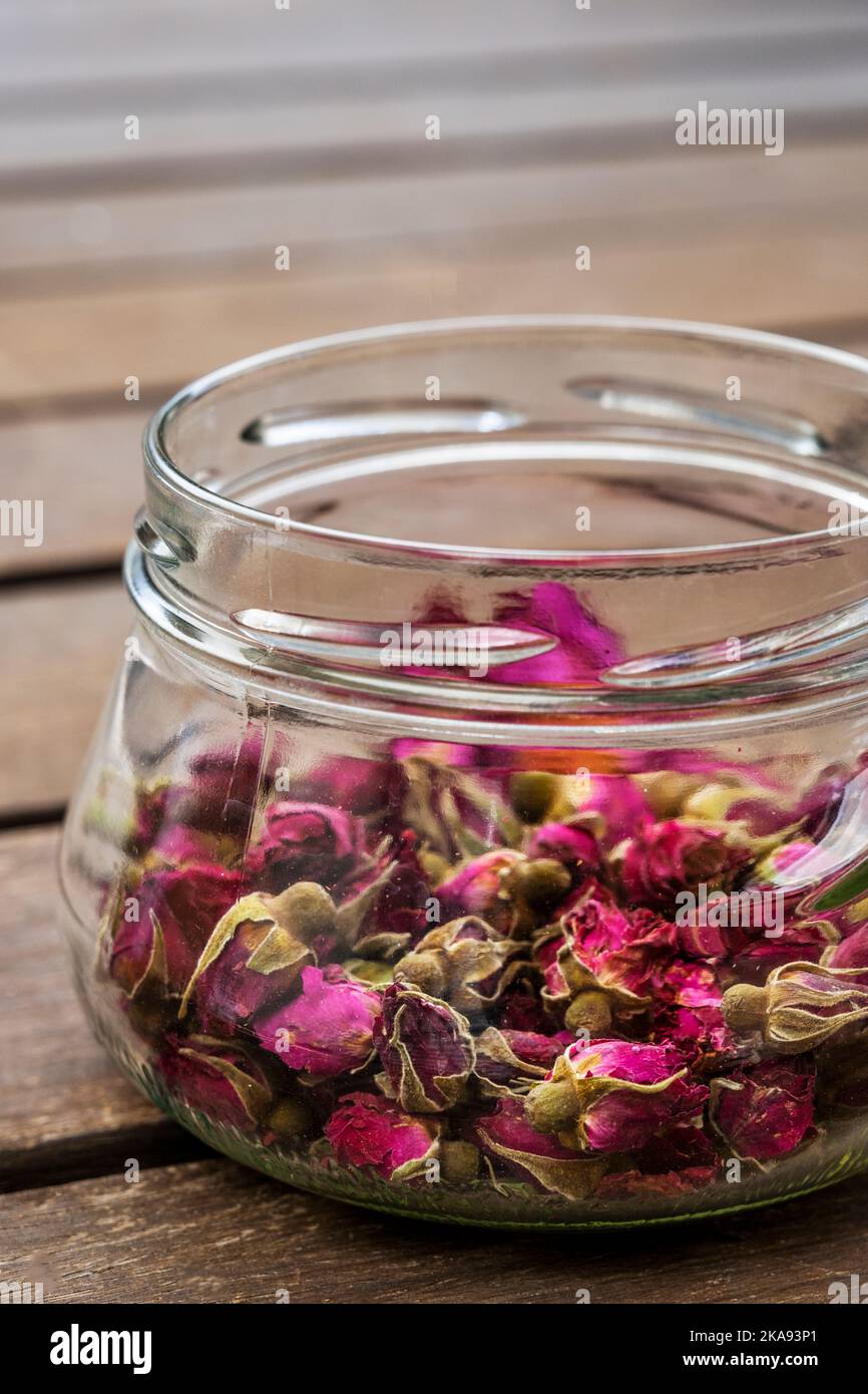 Beautiful glass jars with tea roses on acacia plank surface Stock Photo ...