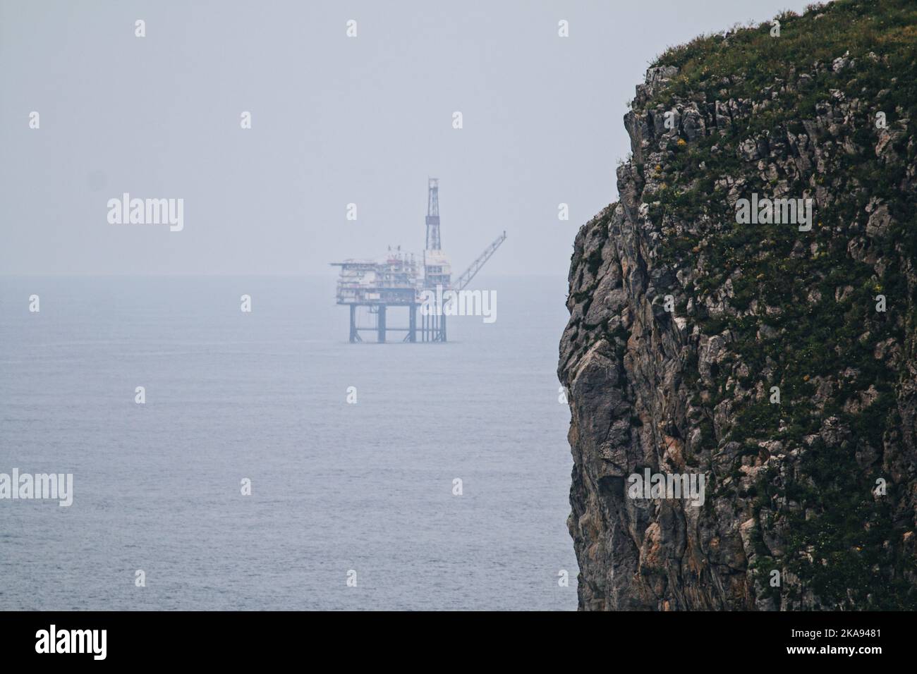The view of the cliff against the oil rig in the distance Stock Photo ...