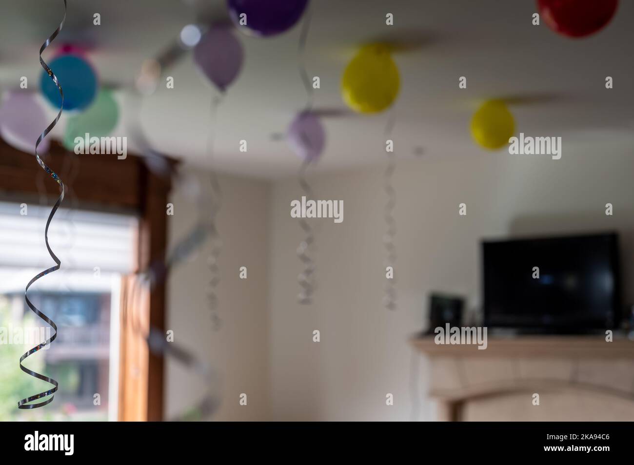 Selective focus on a spiraling silver ribbon attached to a balloon. Blurred balloons in ...
