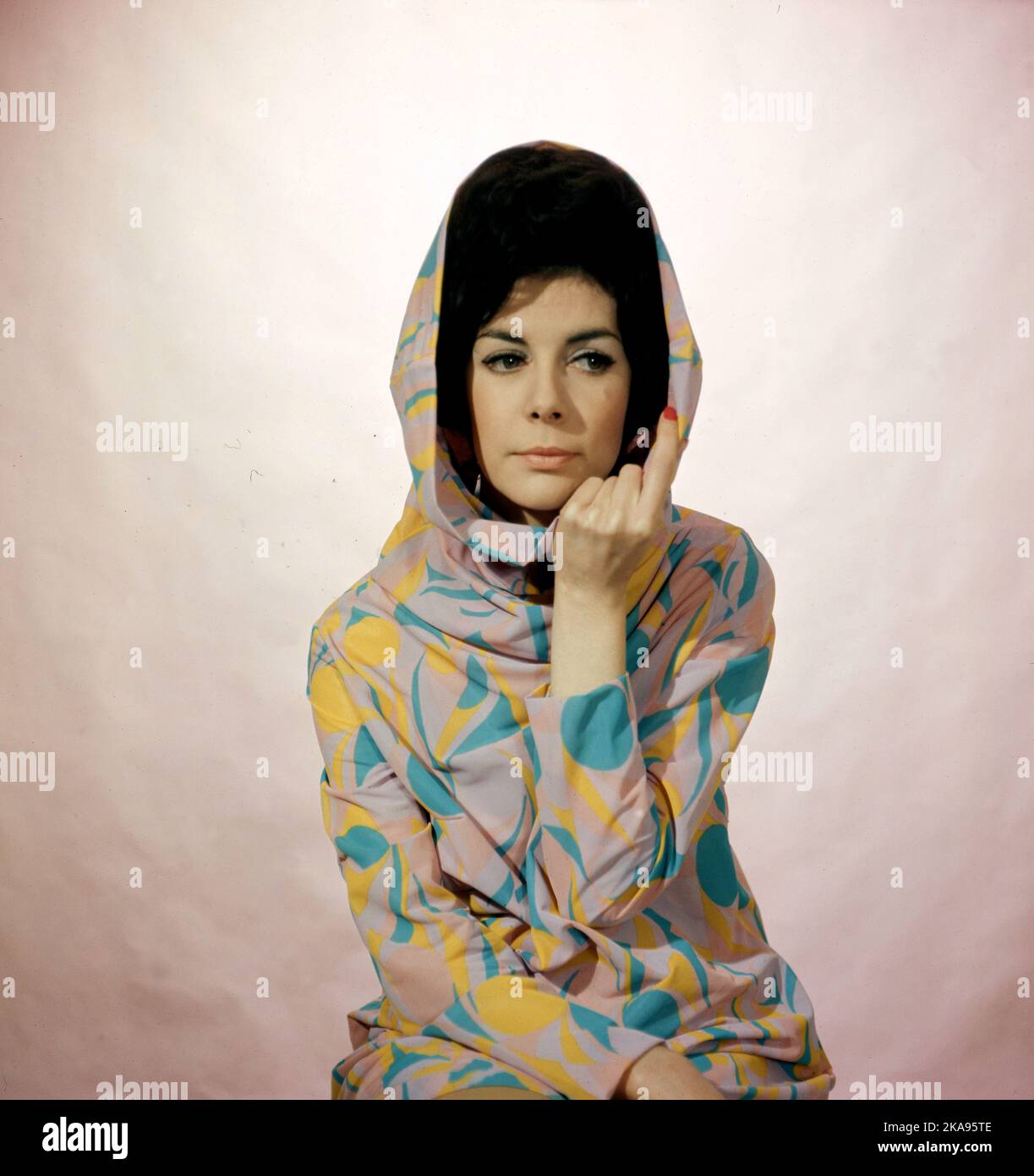 A woman in a hooded top looking into camera with sad expression c1969 ...