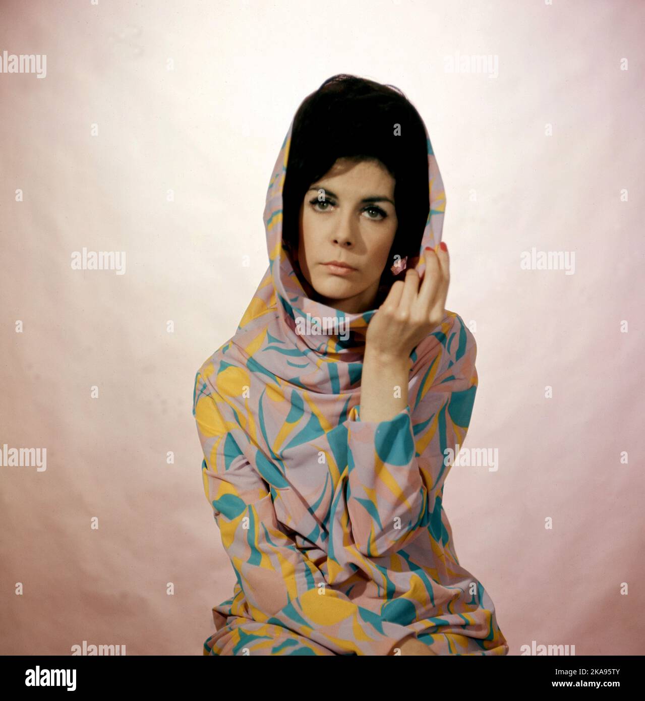 A woman in a hooded top looking into camera with sad expression c1969 ...