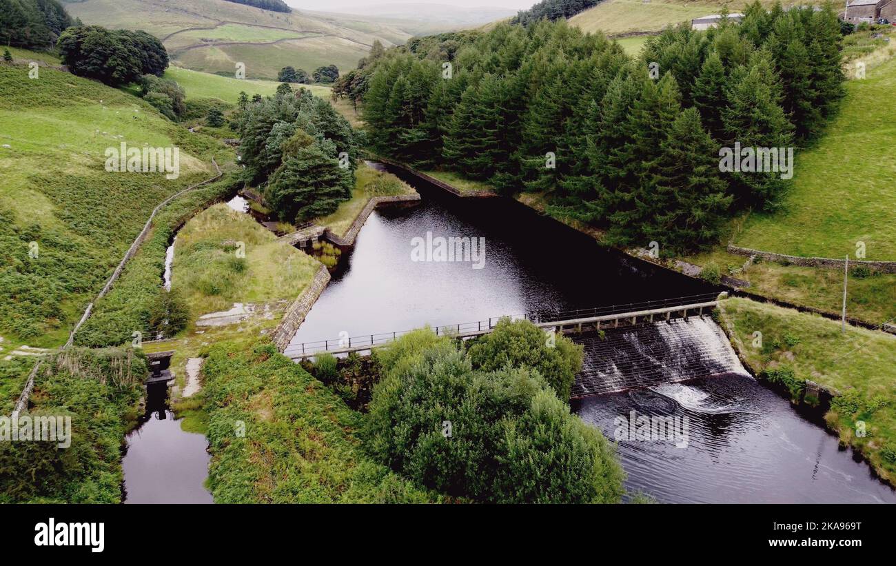 An aerial view of a river flowing down the weir at a reservoir ...