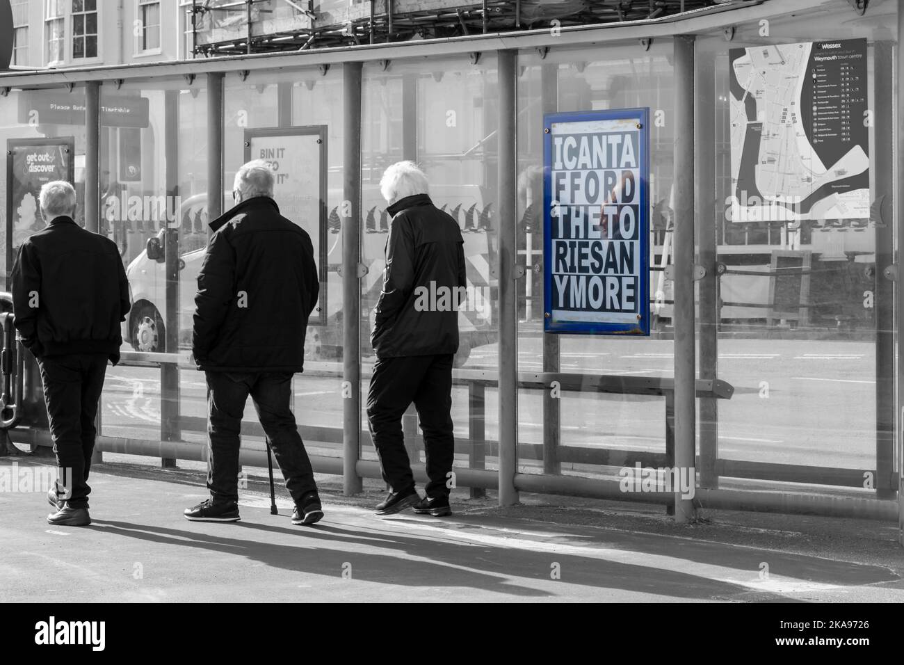 Three men walk past I cant afford the Tories anymore sign at Weymouth ...