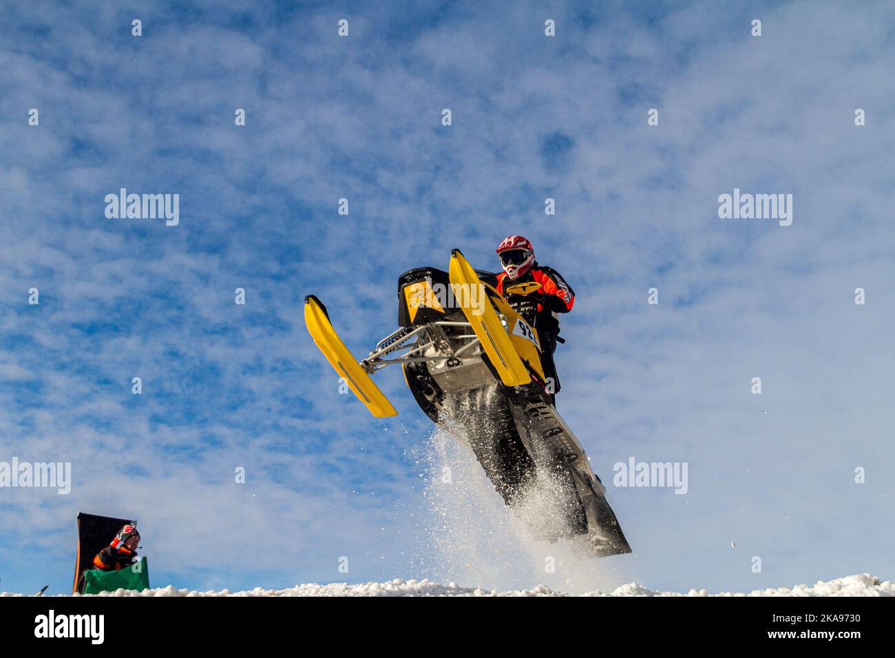 Snowmobiler jumping high above the track. On a snowmobile, a sportsman ...