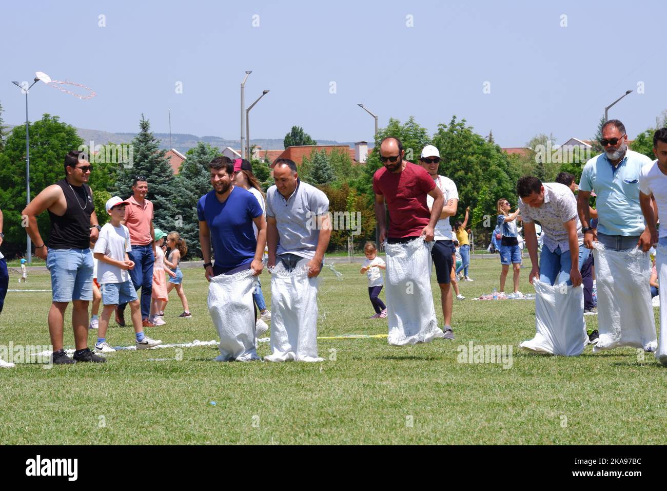People having fun at gunnysack race on grass in a sunny day. Laughing ...