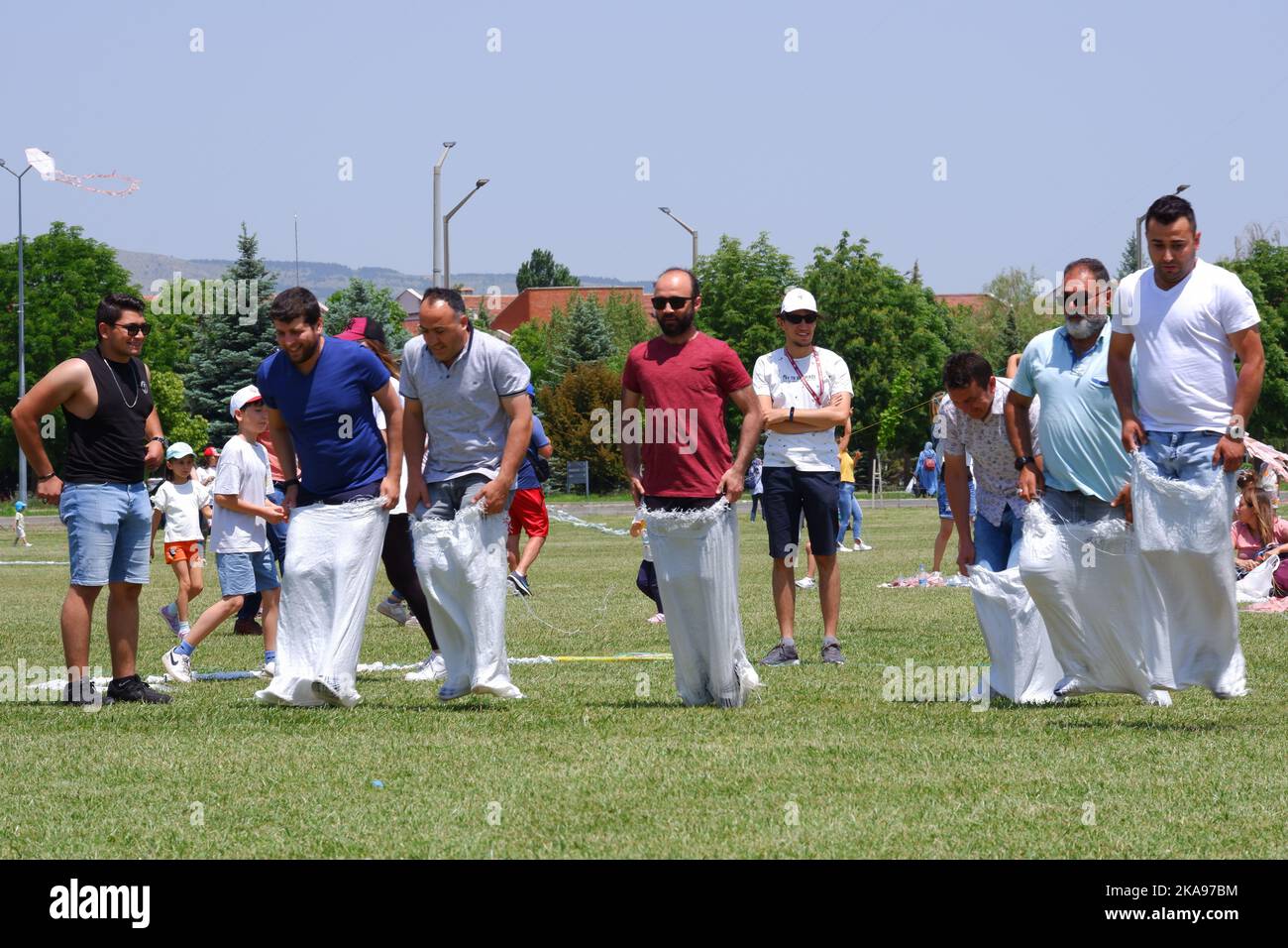 People having fun at gunnysack race on grass in a sunny day. Laughing ...
