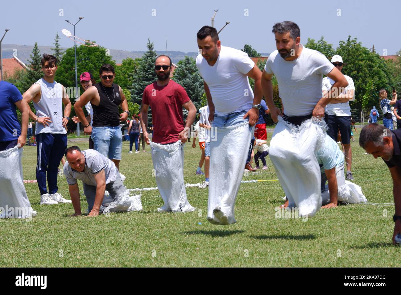 People having fun at gunnysack race on grass in a sunny day. Laughing ...