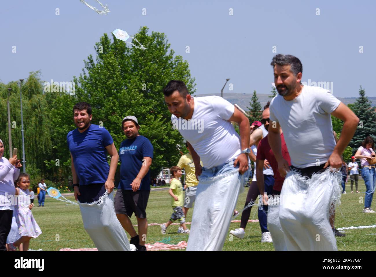 People having fun at gunnysack race on grass in a sunny day. Laughing ...