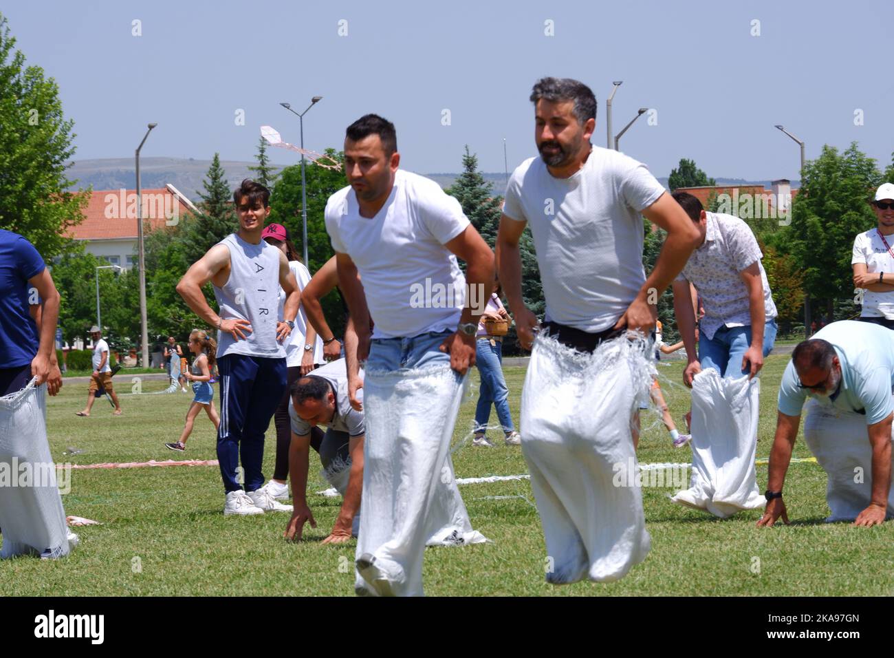 People having fun at gunnysack race on grass in a sunny day. Laughing ...