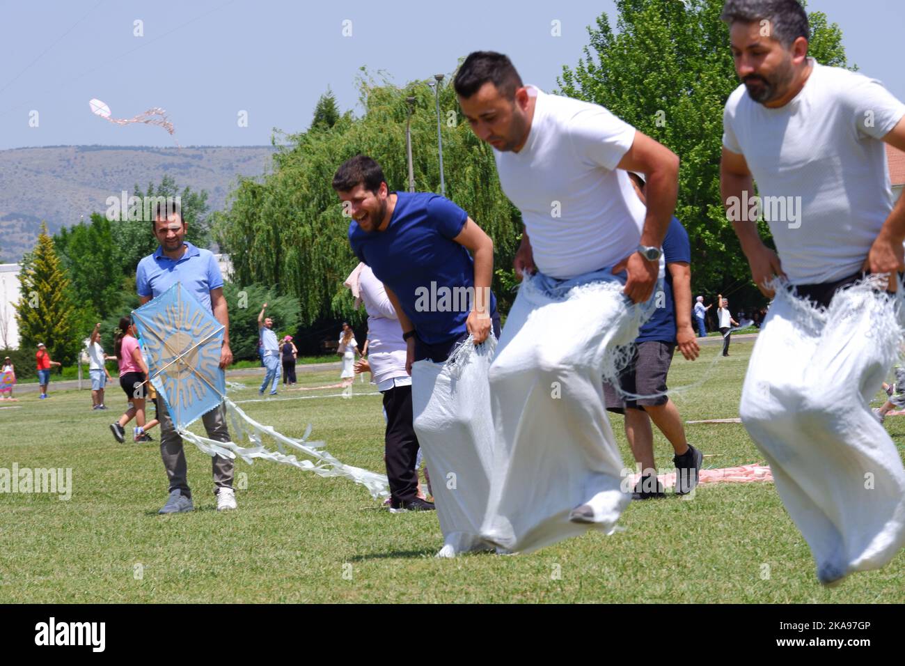 People having fun at gunnysack race on grass in a sunny day. Laughing ...