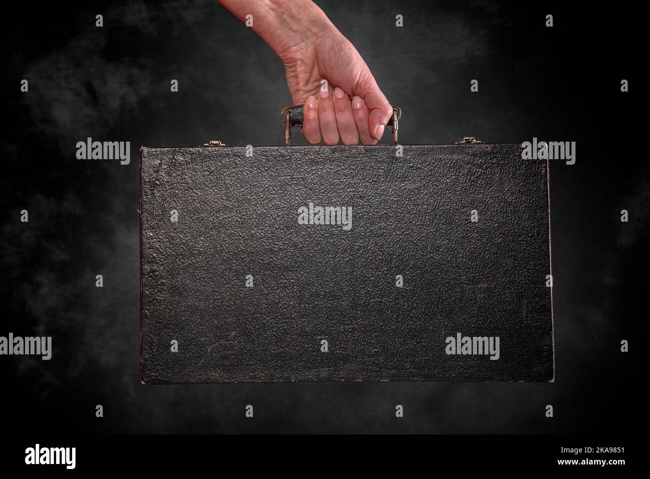 Old suitcase in a female hand on a dark background Stock Photo - Alamy