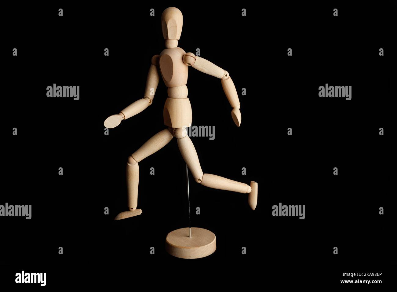 A wooden doll mannequin with movable body parts in a running pose ...