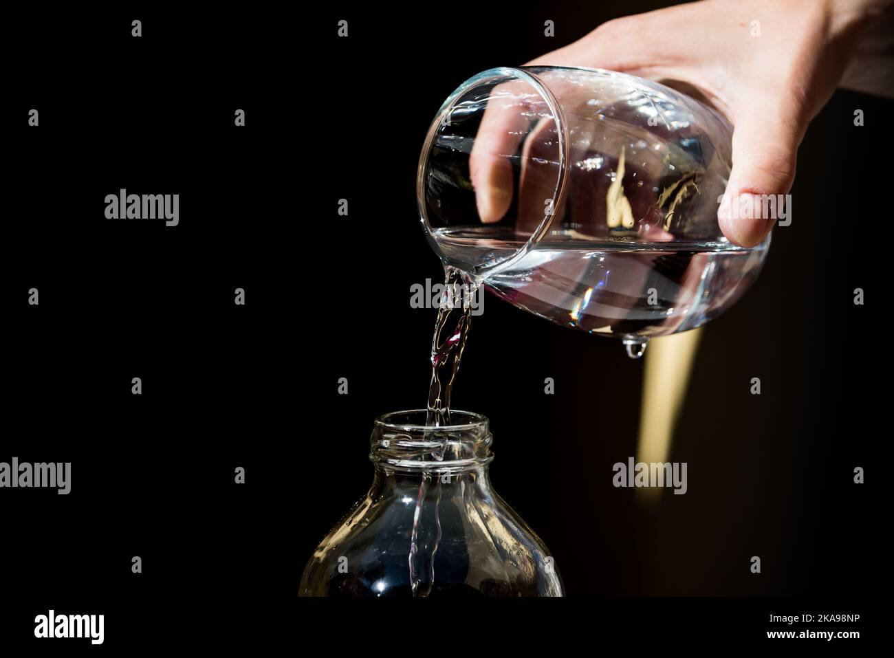 A closeup of a hand pouring water from glass a into a bottle Stock ...