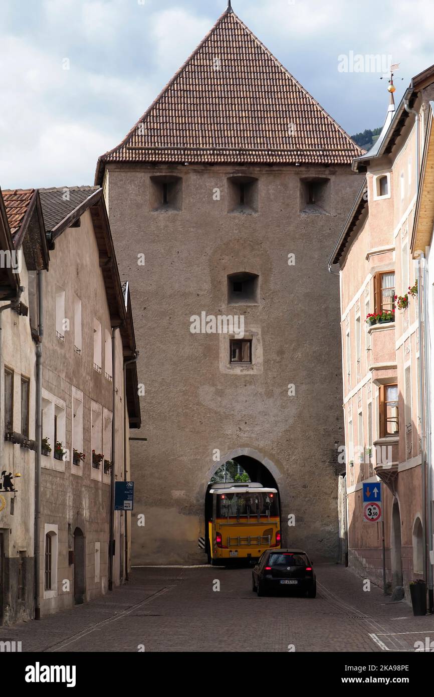 a sinlge deck bus squeezes through a medieval gate in the walled town ...