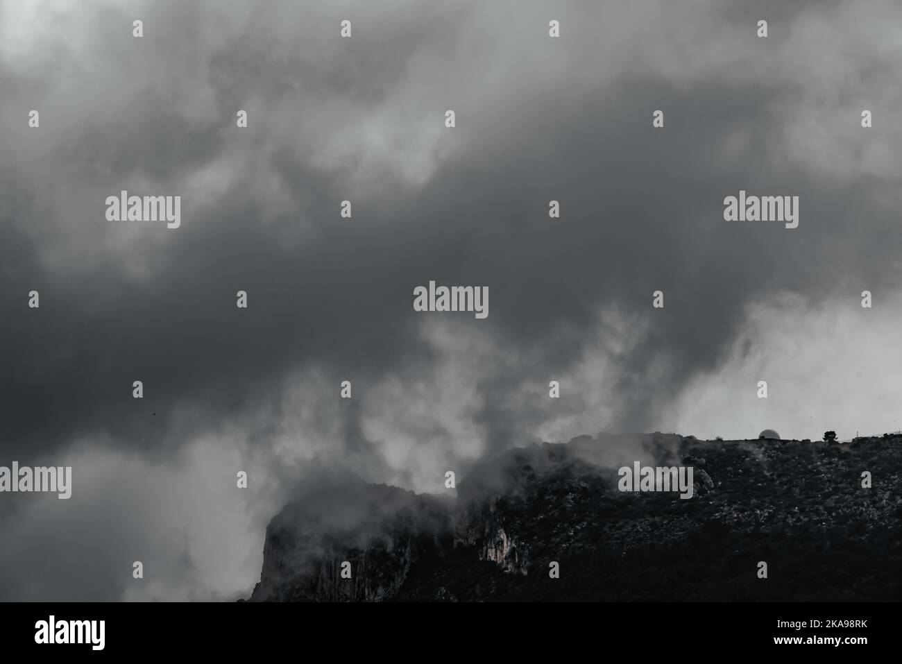 The dark peak of the mountain covered with gray clouds. Monte Carlo ...