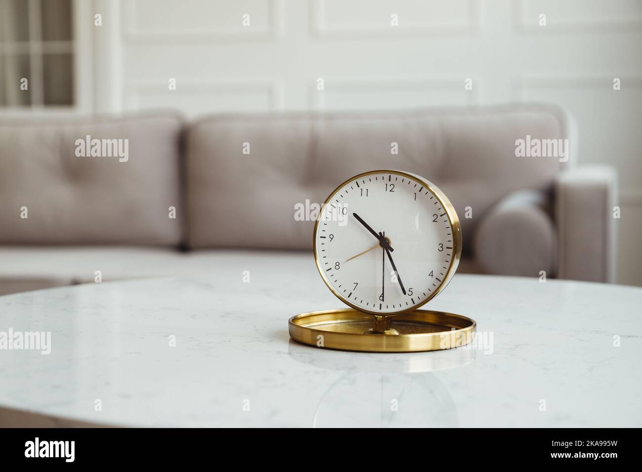 Table clock on a coffee table in a living room with a gray sofa ...