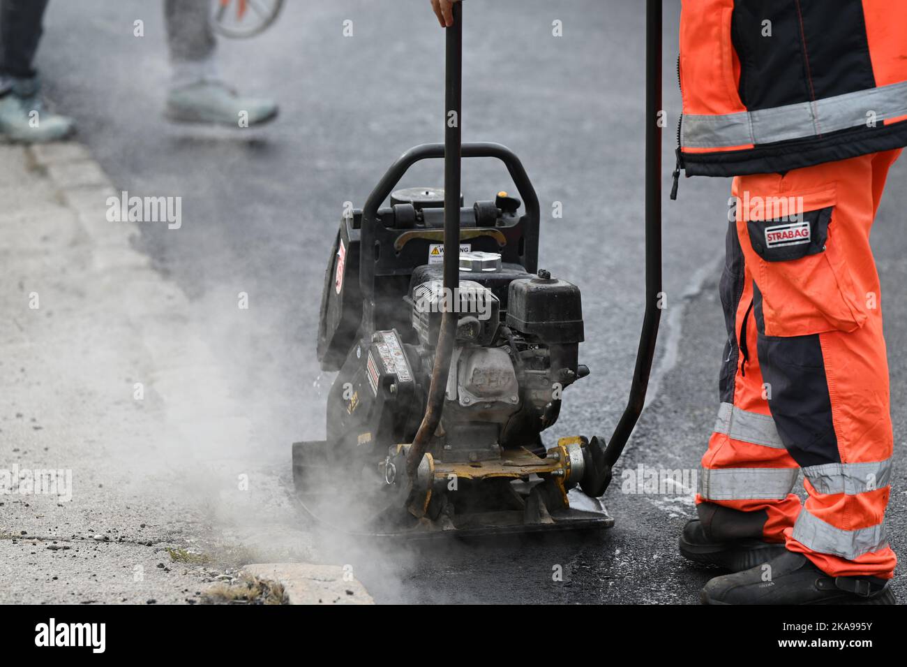 A plate compactor for compacting asphalt at a road construction site ...