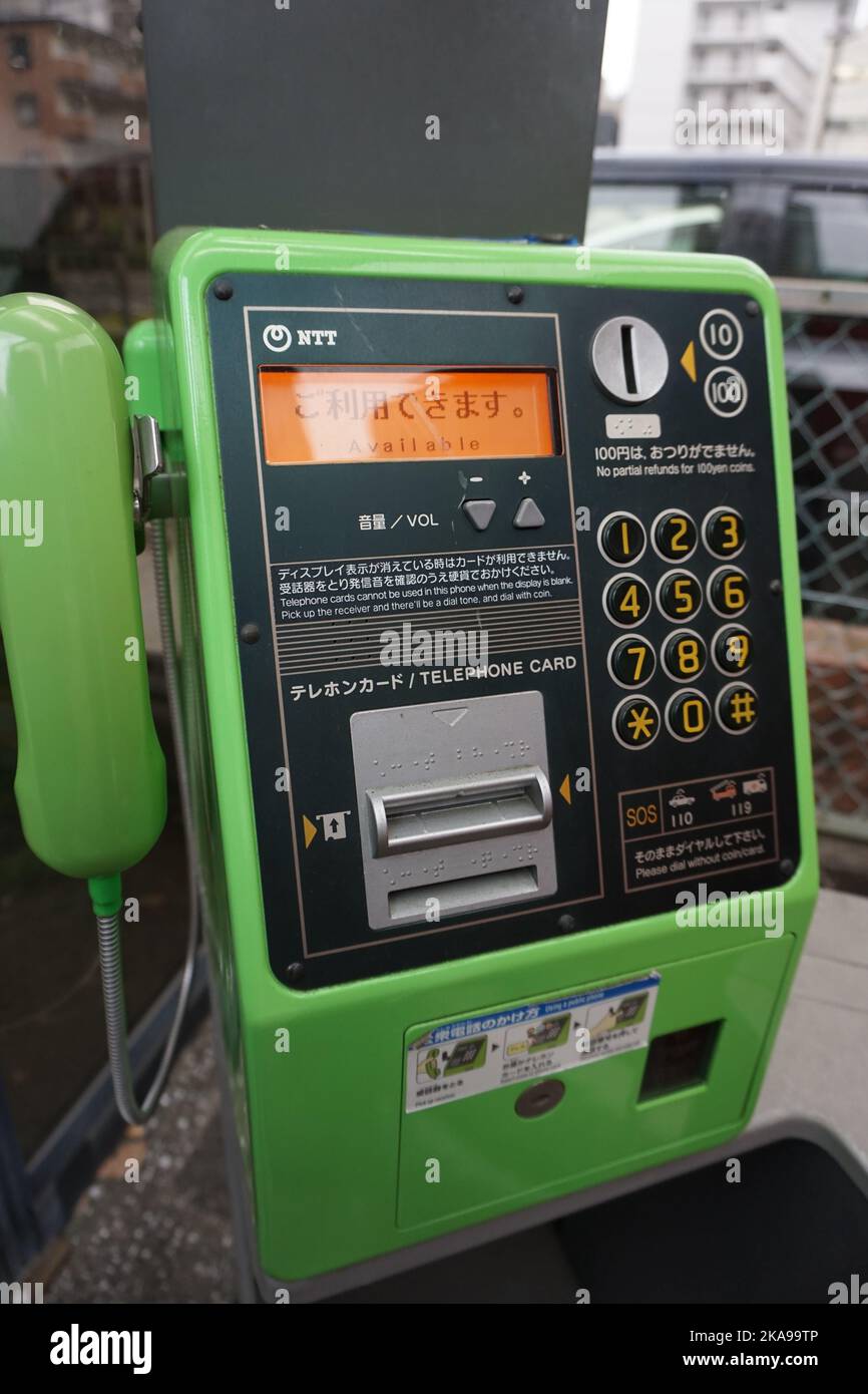 A vertical closeup of a green payphone in an NTT Phone booth in ...