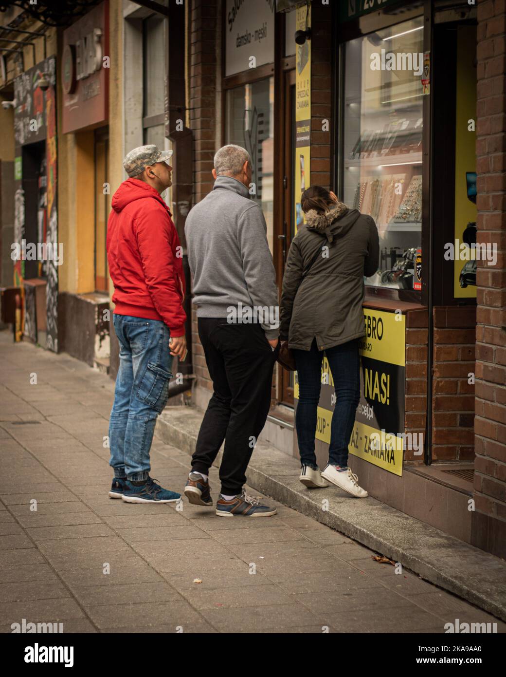 A vertical back view of a group of people doing window shopping in the ...