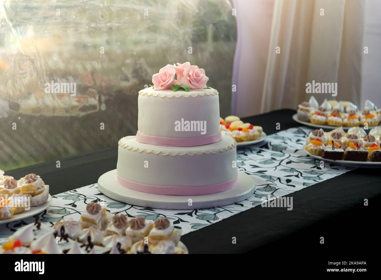 A two-floor floral cake and different sweets on a table in a wedding ...