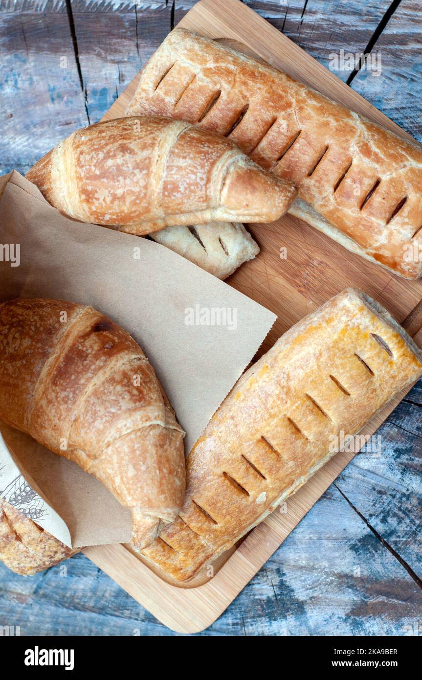 A closeup of delicious fresh puff pastry and croissants on a wooden ...